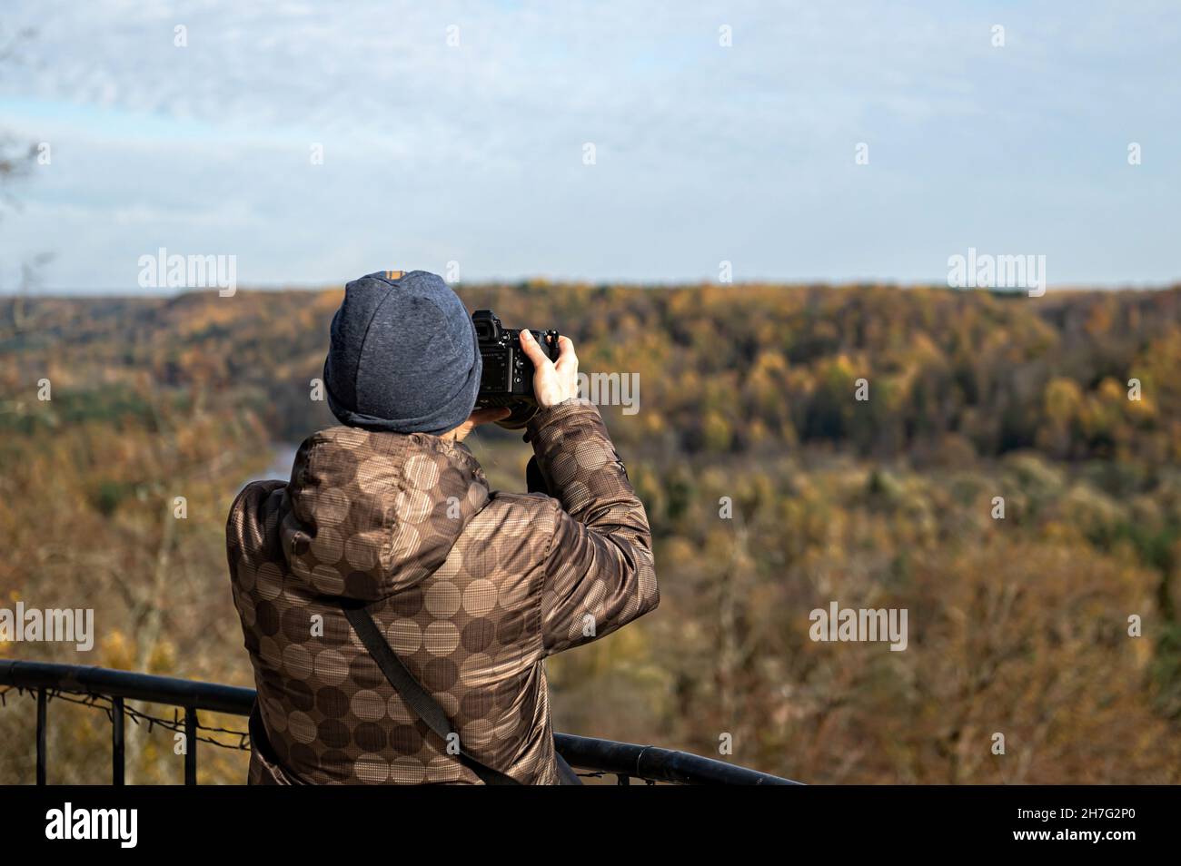back view of Young photographer takes pictures of autumn landscape ...