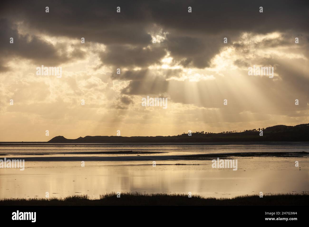 Shafts of sun ray light breaking through clouds at Malltraeth Anglesey ...