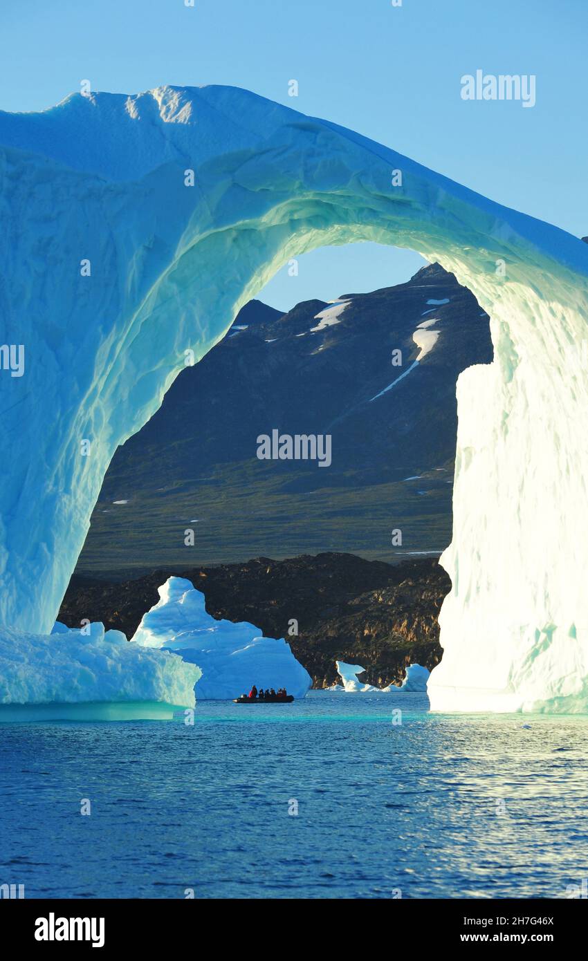 DENMARK. GREENLAND. WEST COAST. ZODIAC NEAR AN ARCH SHAPED ICEBERG IN ...