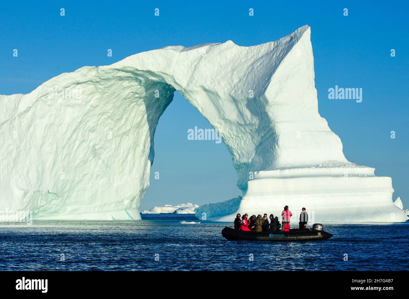 DENMARK. GREENLAND. WEST COAST. ZODIAC NEAR AN ARCH SHAPED ICEBERG IN ...
