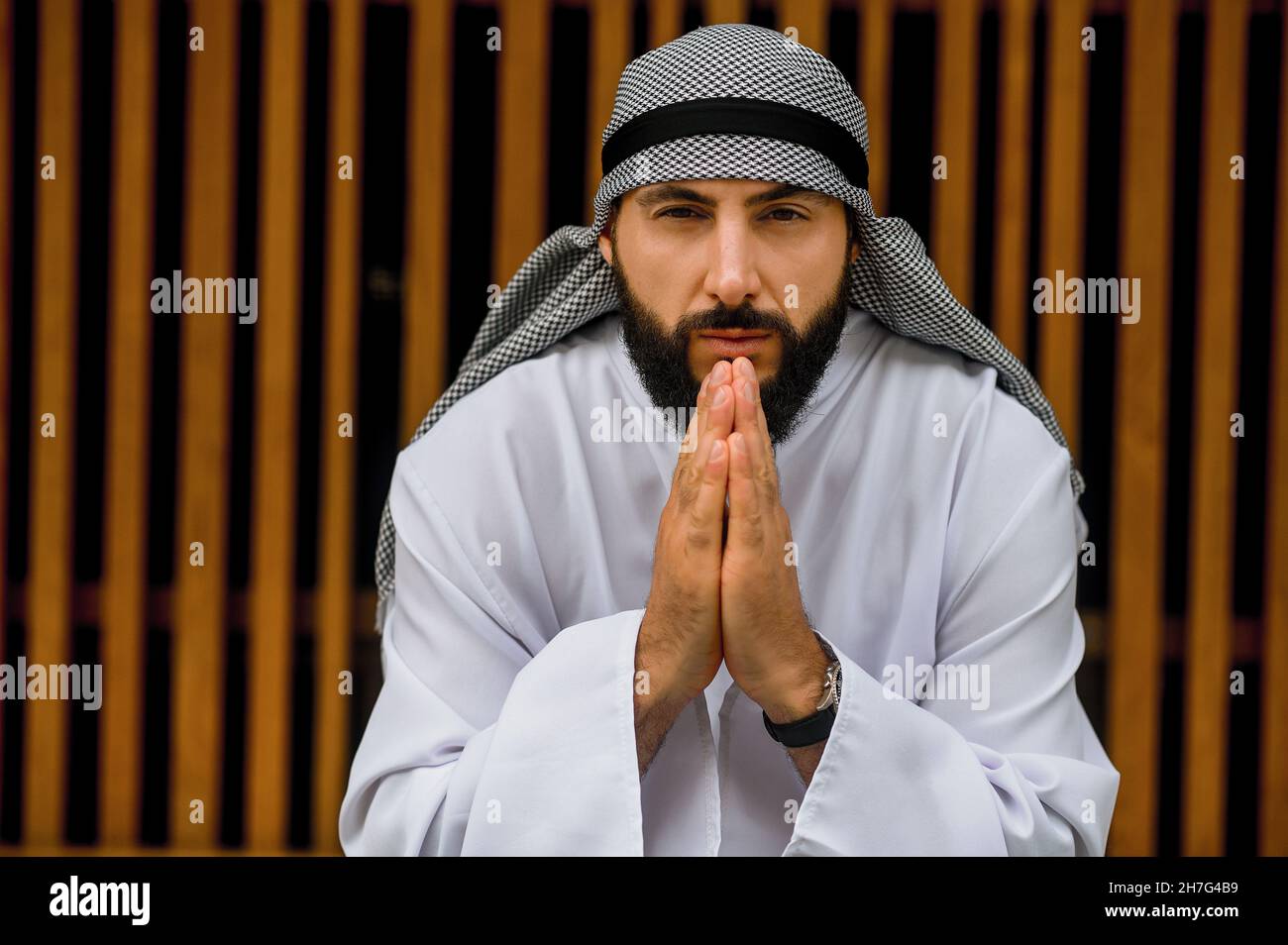 Middle eastern young man in traditional clothing looking thoughtful and ...