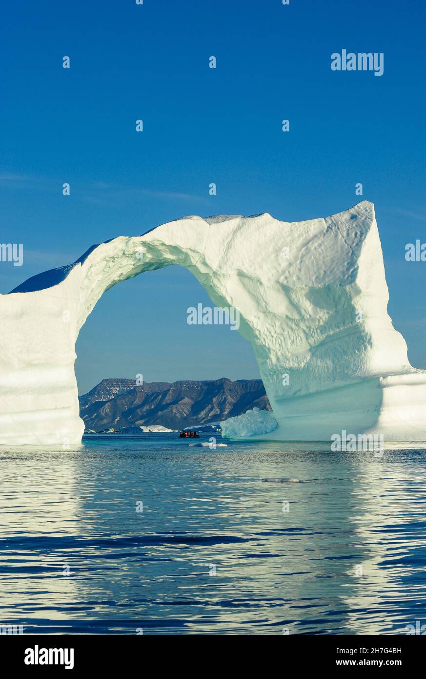 DENMARK. GREENLAND. WEST COAST. ZODIAC NEAR AN ARCH SHAPE ICEBERG IN ...