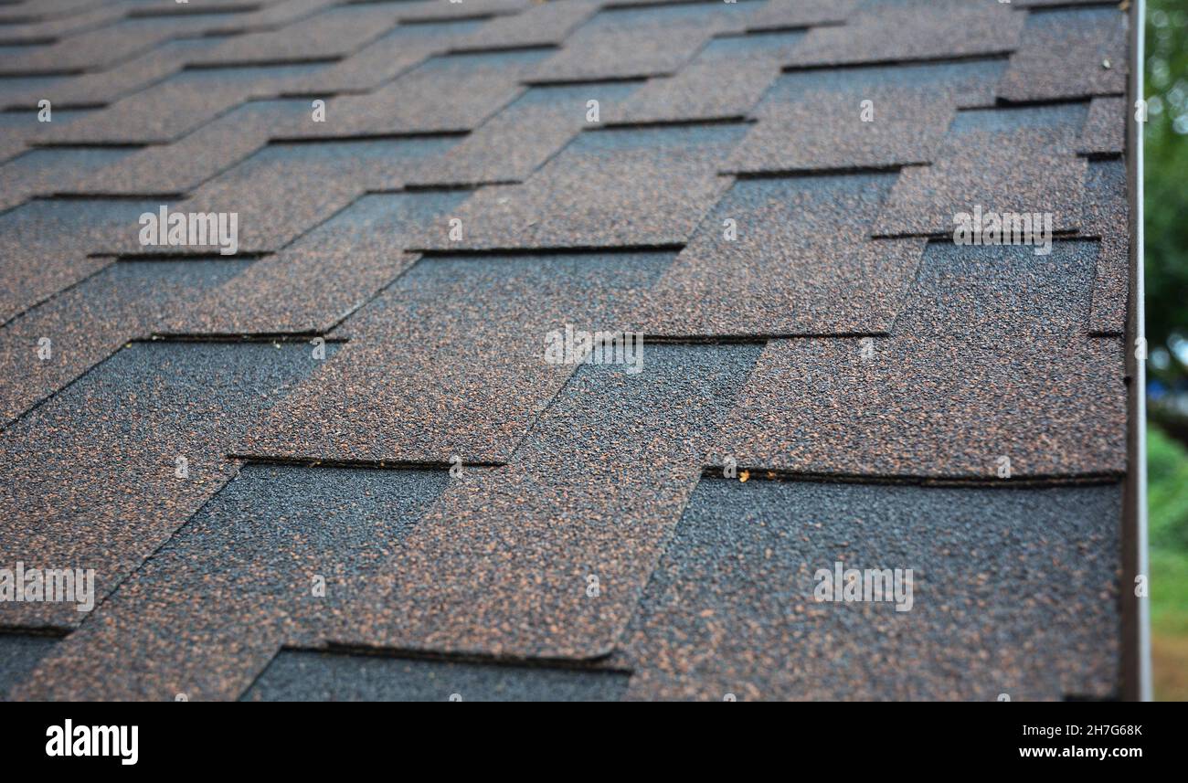 A close-up of asphalt shingles installation on the edge of the roof ...