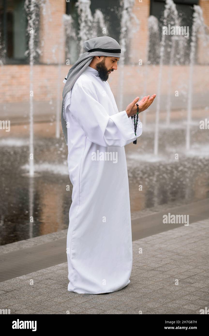 Young bearded arabian man in traditional clothing praying Stock Photo ...
