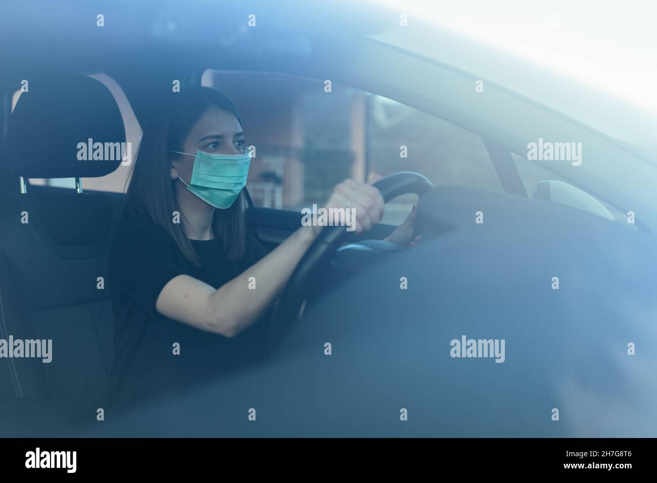 Caucasian female in a face mask driving a car Stock Photo - Alamy
