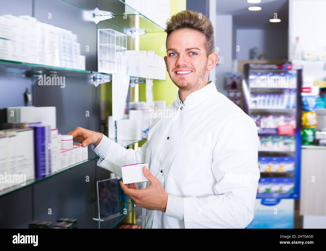 Happy pharmacist standing among shelves Stock Photo - Alamy