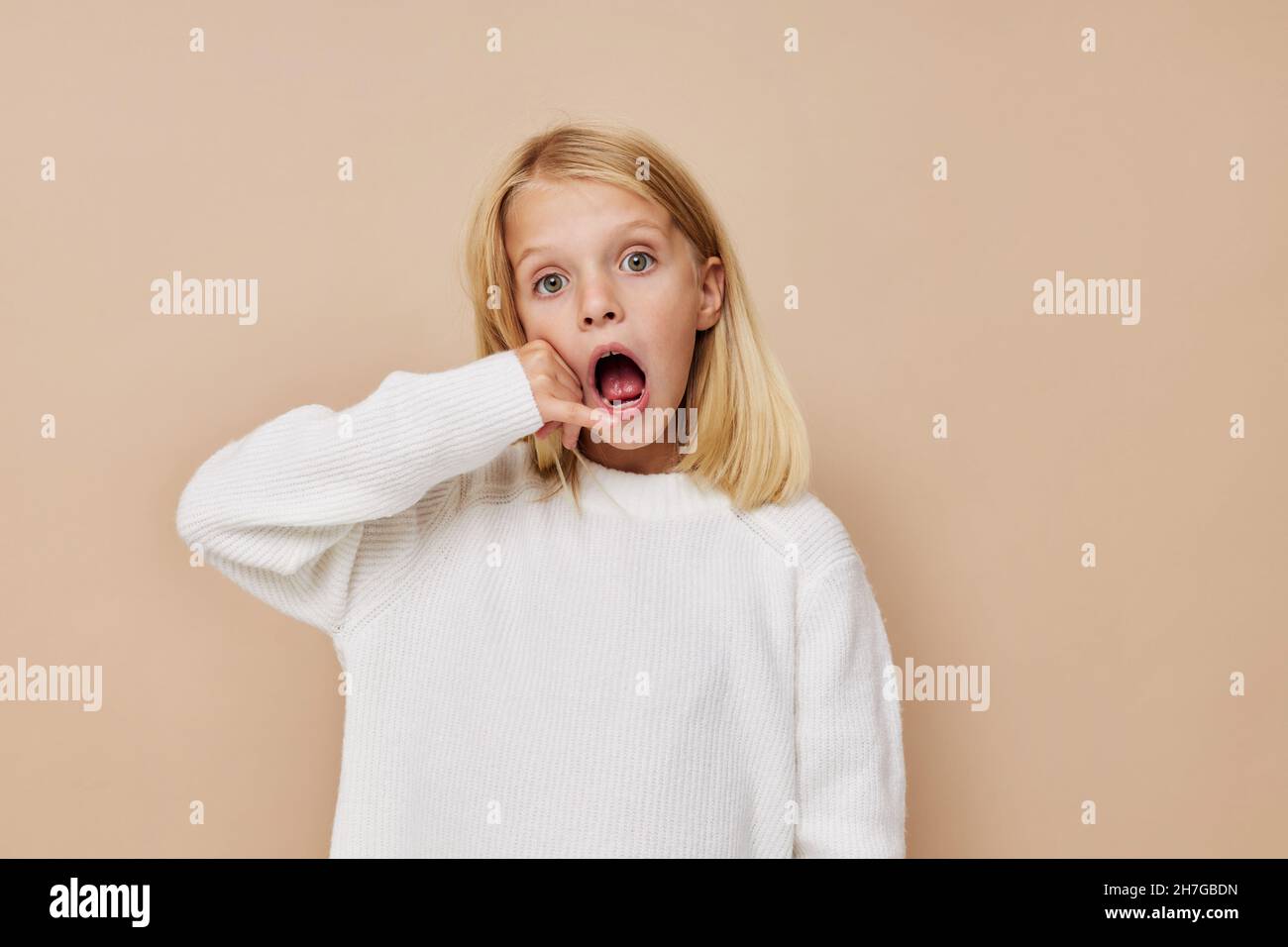 Beautiful little girl with blond hair on a beige background Stock Photo ...