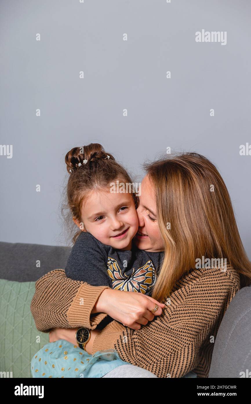 Mom hugs her daughter tightly while sitting on a cozy home sofa Stock Photo - Alamy