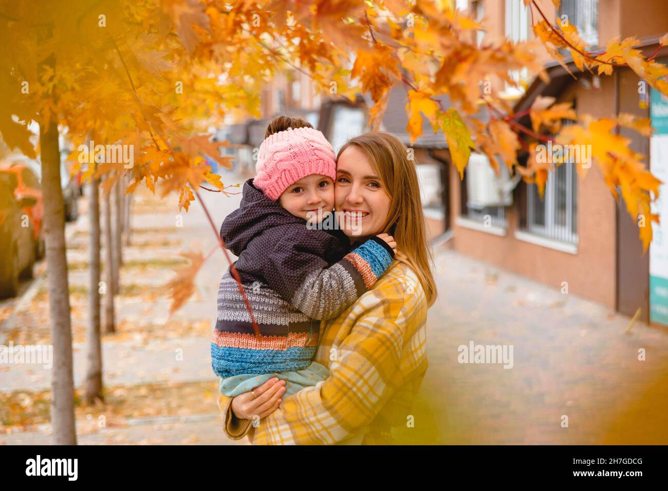 Portrait of happy and beautiful mother with her daughter in her arms ...