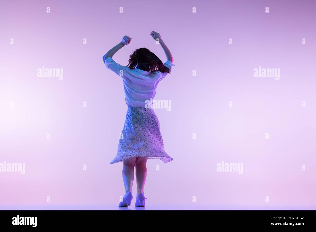 Back view of young excited woman in vintage retro style clothes dancing ...