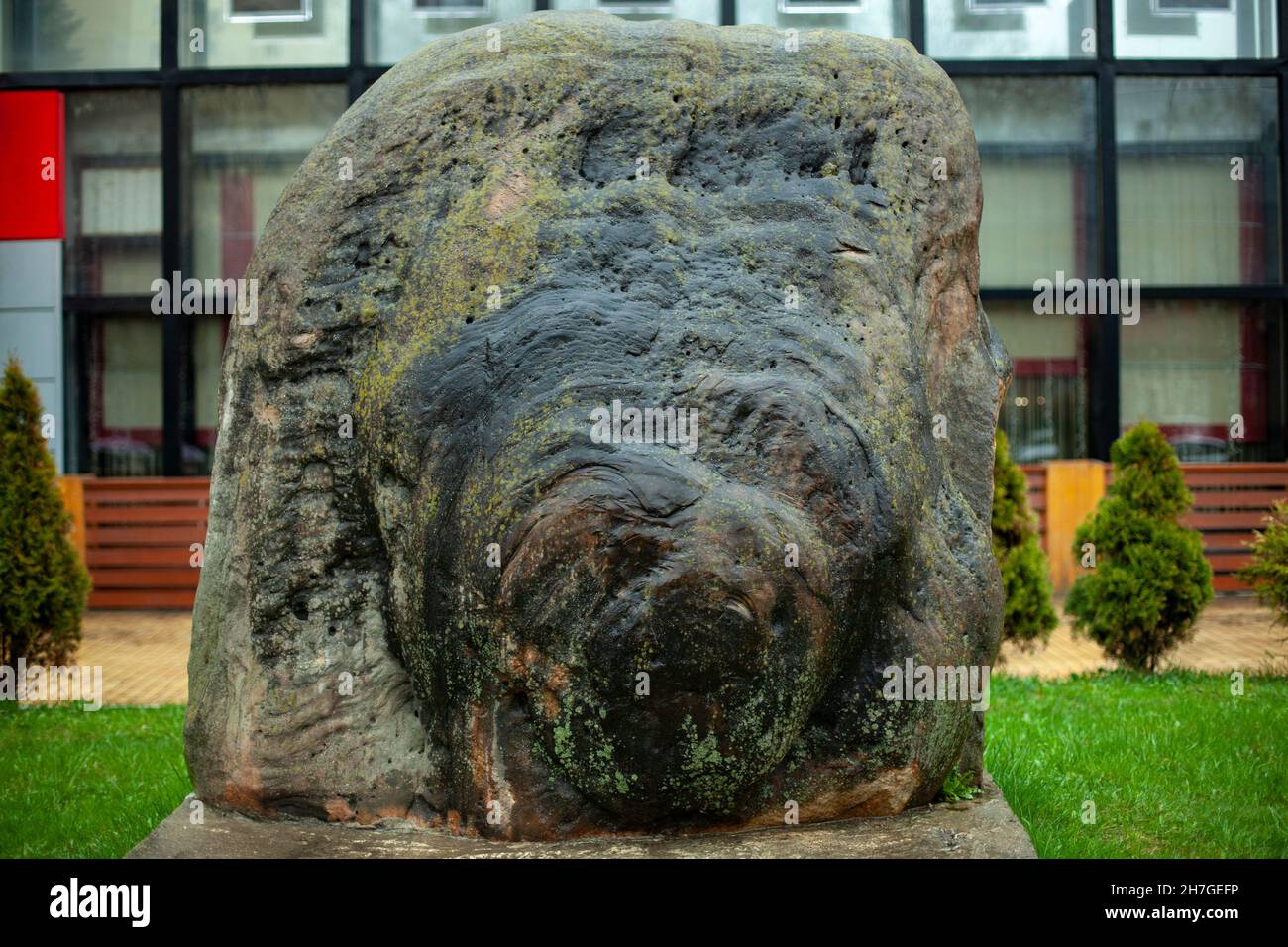 Stone in the city. A wet giant shard of rock is installed on the street ...