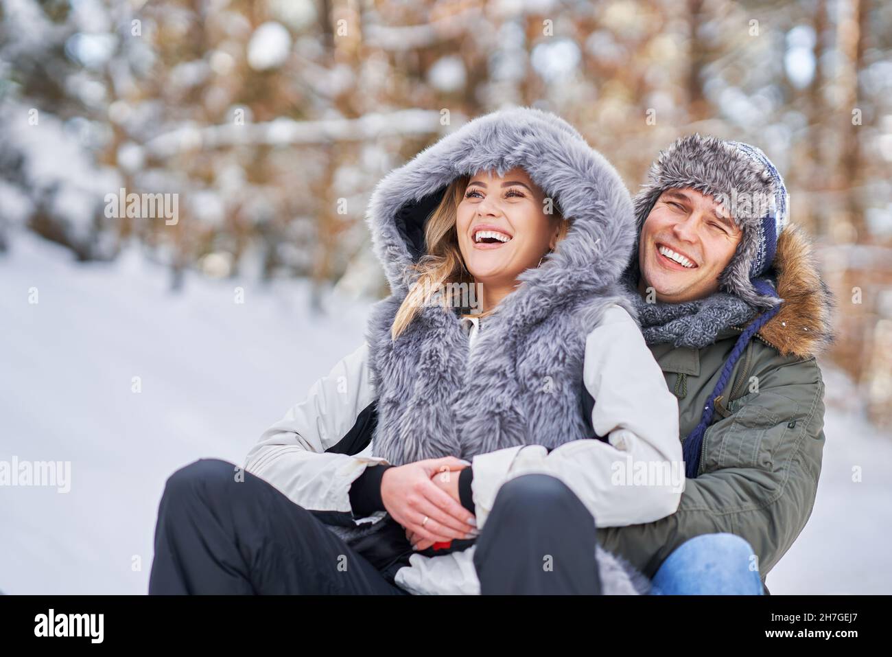 Couple having fun with sledge on snow in winter Stock Photo - Alamy