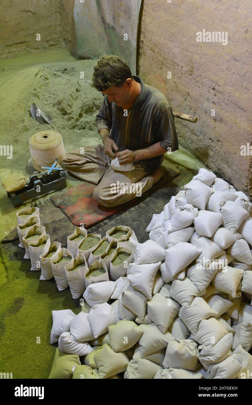 IRAN. YAZD. HENNA MILL IN THE BAZAAR OF YAZD. MAN PUTTING THE HENNA ...