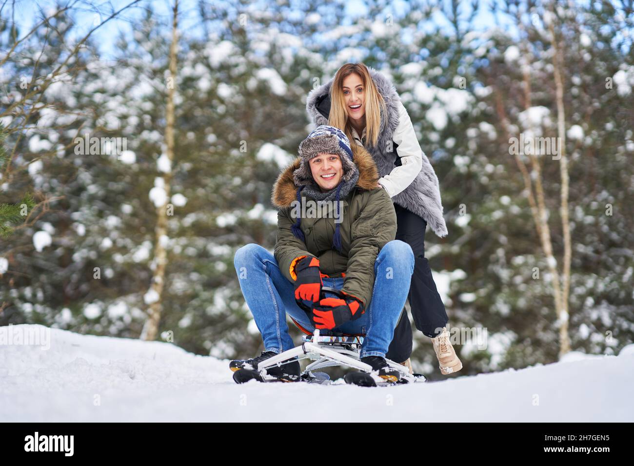 Couple having fun with sledge on snow in winter Stock Photo - Alamy