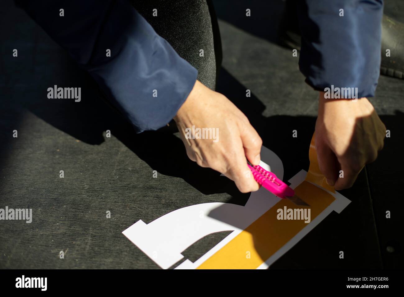 Cutting the adhesive tape. Work with a conceler knife. A person glues a ...