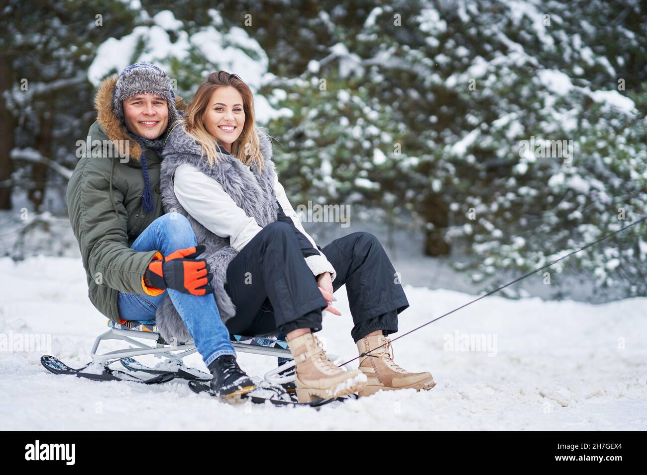 Couple having fun with sledge on snow in winter Stock Photo - Alamy