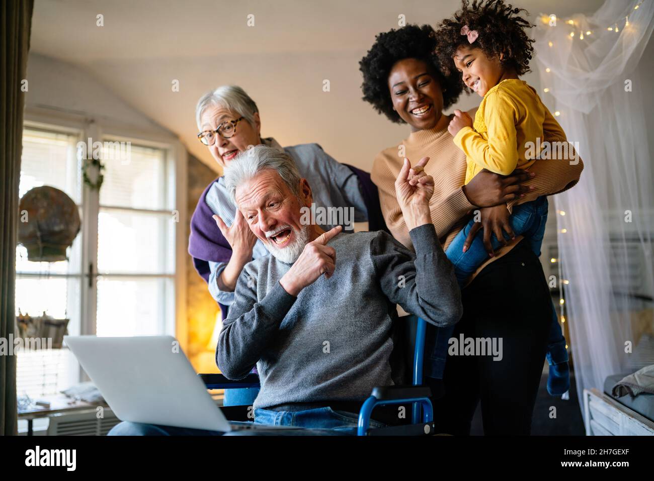 Happy multi-generation family gathering around notebbok and having fun ...