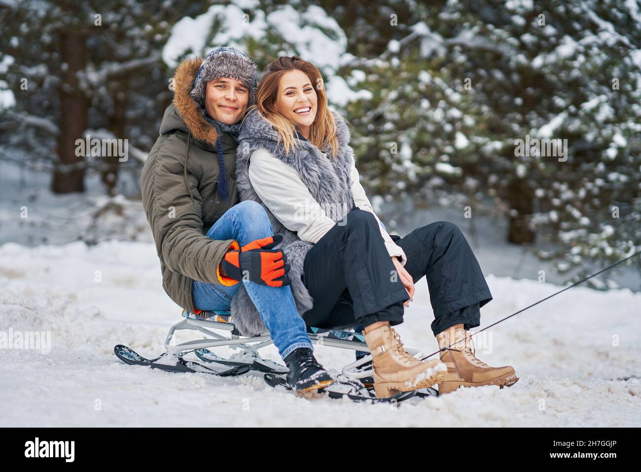 Couple having fun with sledge on snow in winter Stock Photo - Alamy