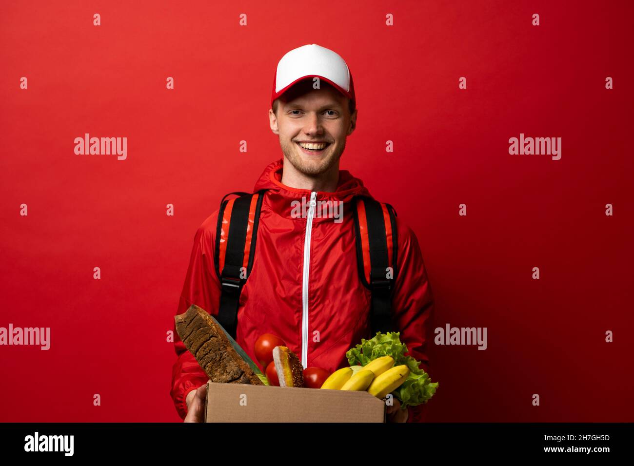 Delivery man in a red uniform with a thermal bag on a shoulder ...