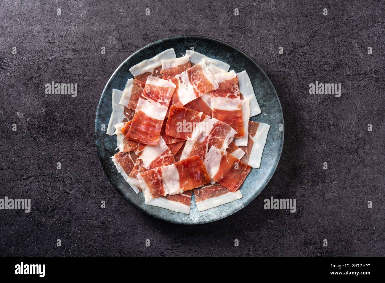 Spanish serrano ham slice on black slate background Stock Photo - Alamy