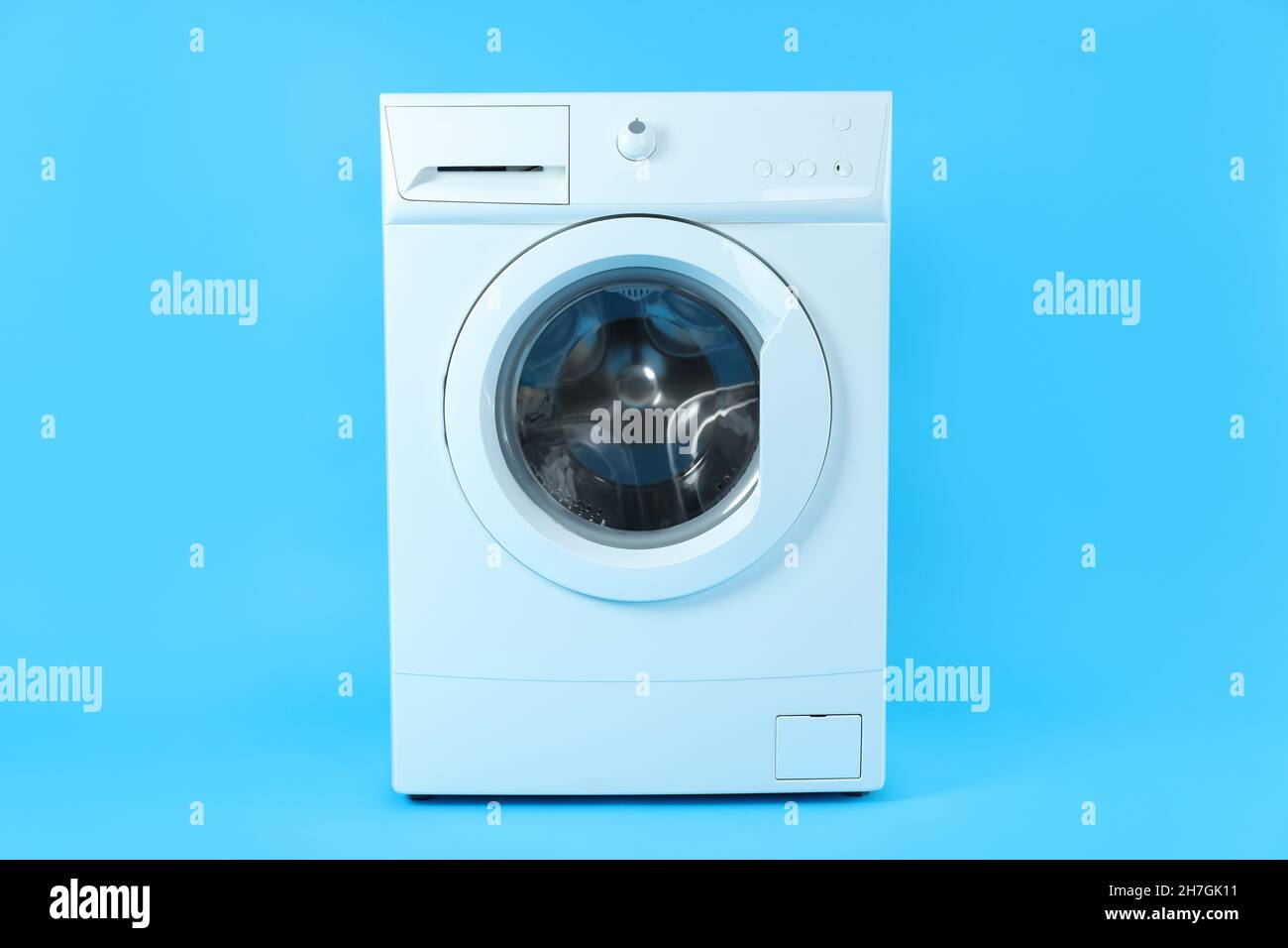 Modern white washing machine on blue background Stock Photo - Alamy