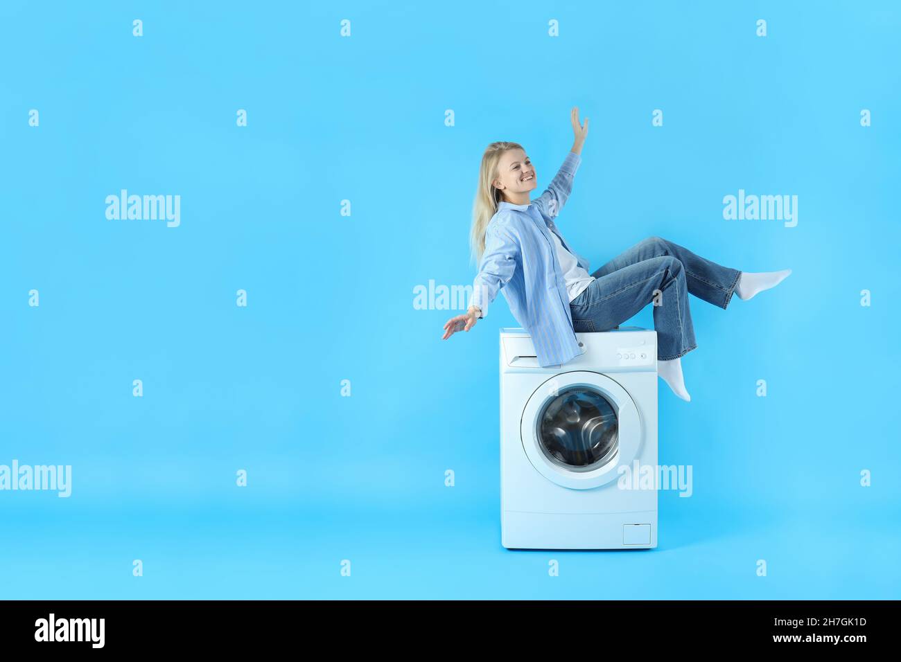Concept of housework with washing machine and girl on blue background ...