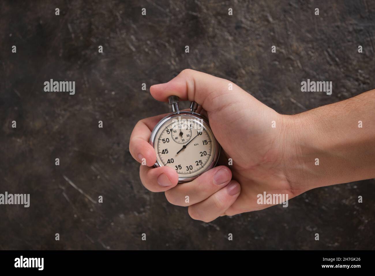 Stopwatch in a man hand on a dark concrete background. Sports, movement ...