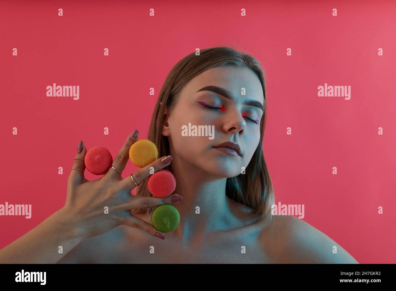 Beautiful model girl with macarons on pink background Stock Photo - Alamy