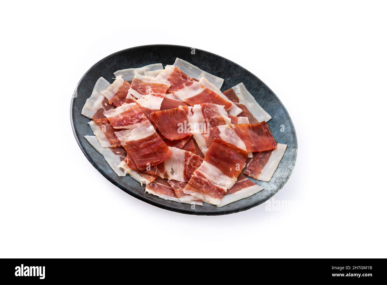 Spanish serrano ham slice on black plate isolated on white background ...