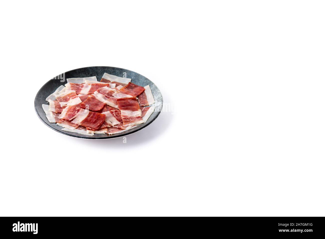 Spanish serrano ham slice on black plate isolated on white background ...