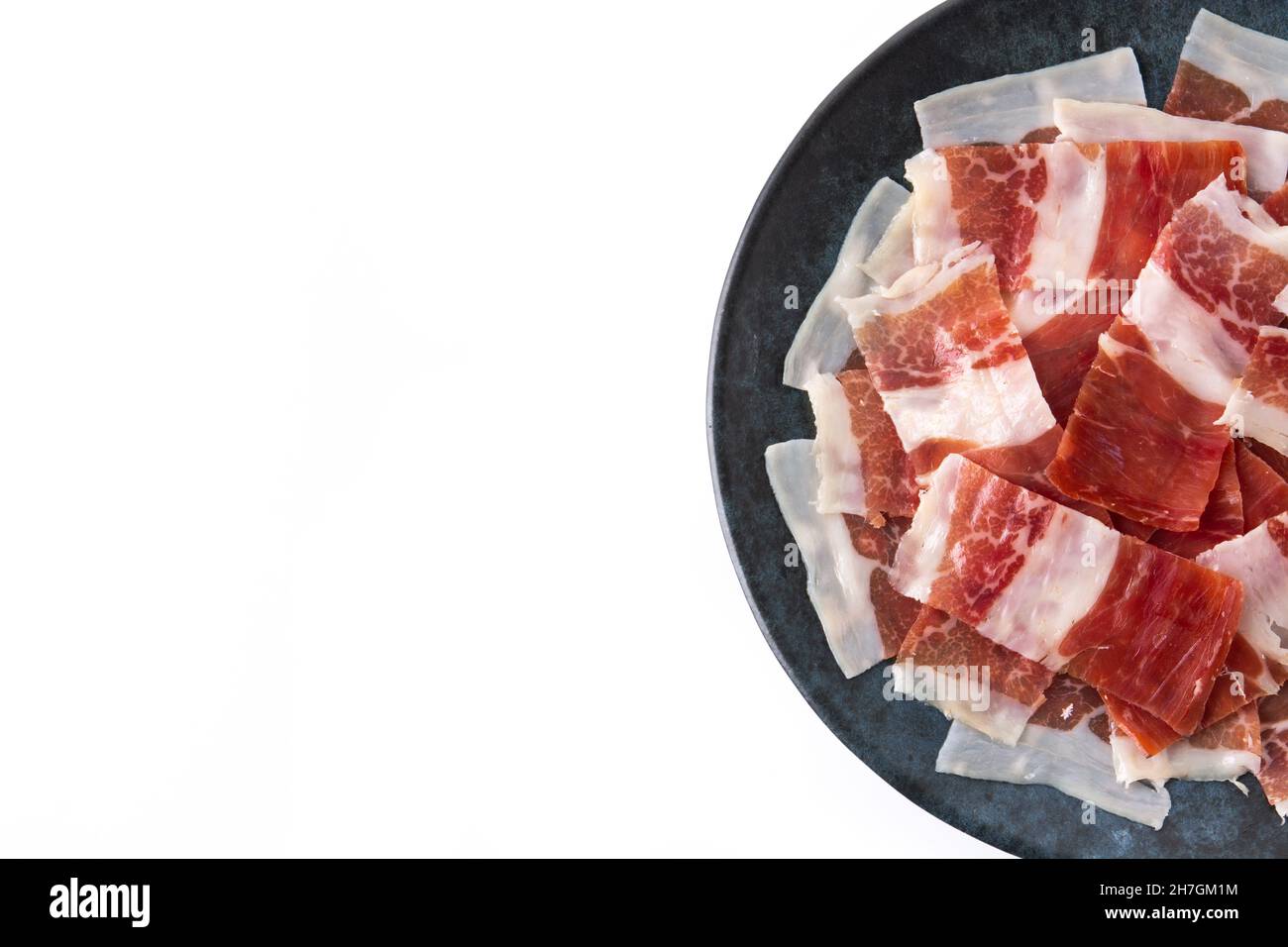 Spanish serrano ham slice on black plate isolated on white background ...