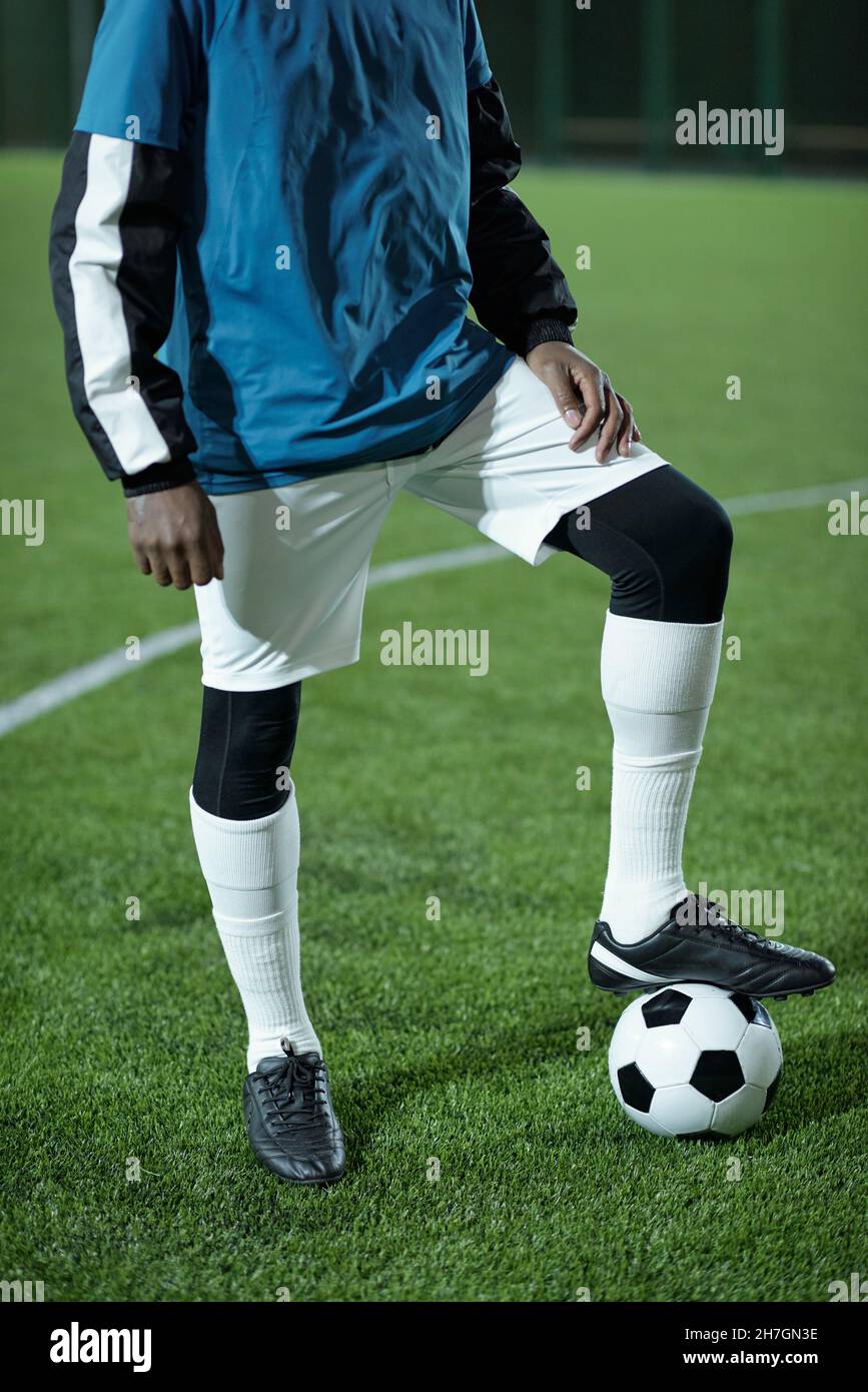 Young African football player in uniform keeping foot on soccer ball ...