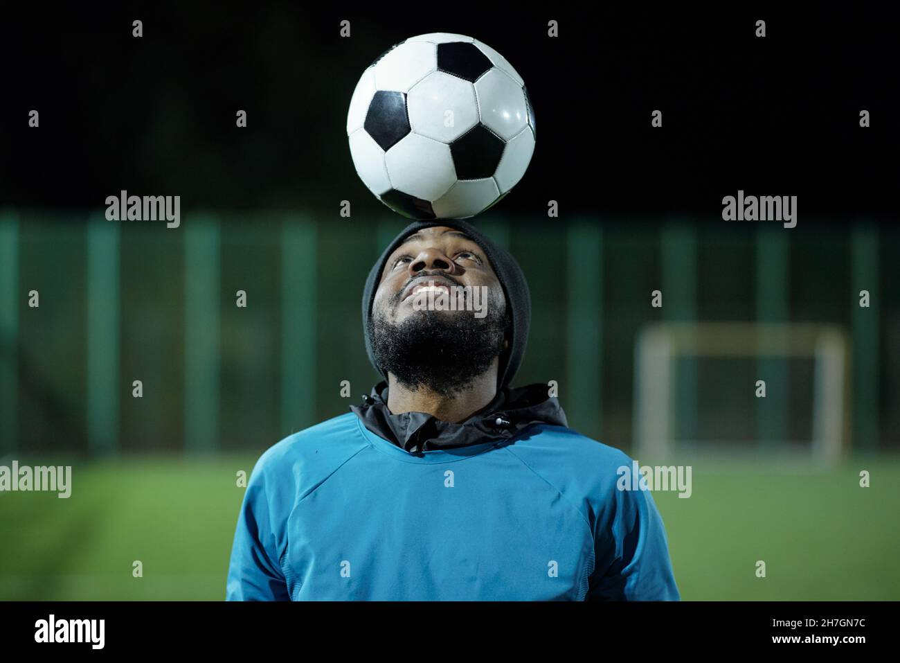 Bearded blackman in sports uniform looking at soccer ball on his ...