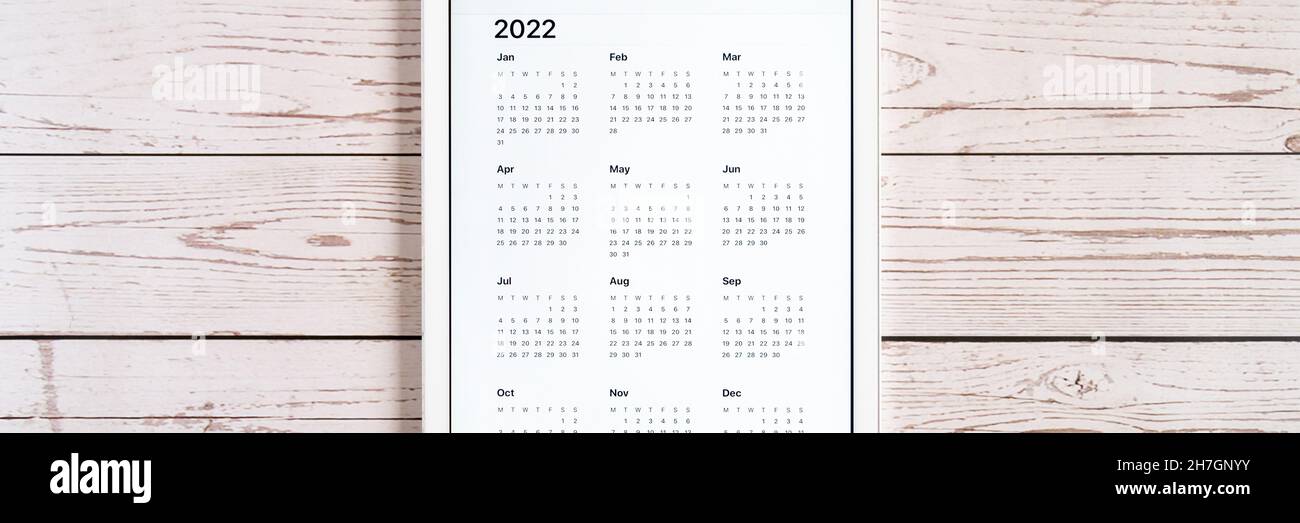 tablet computer with an open app of calendar for 2022 year on a wooden ...