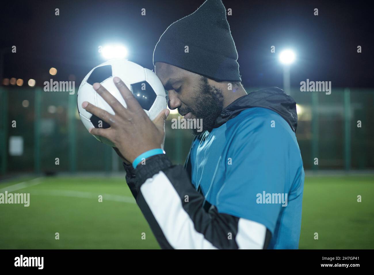 Side view of young sportsman with soccer ball by his forehead standing ...