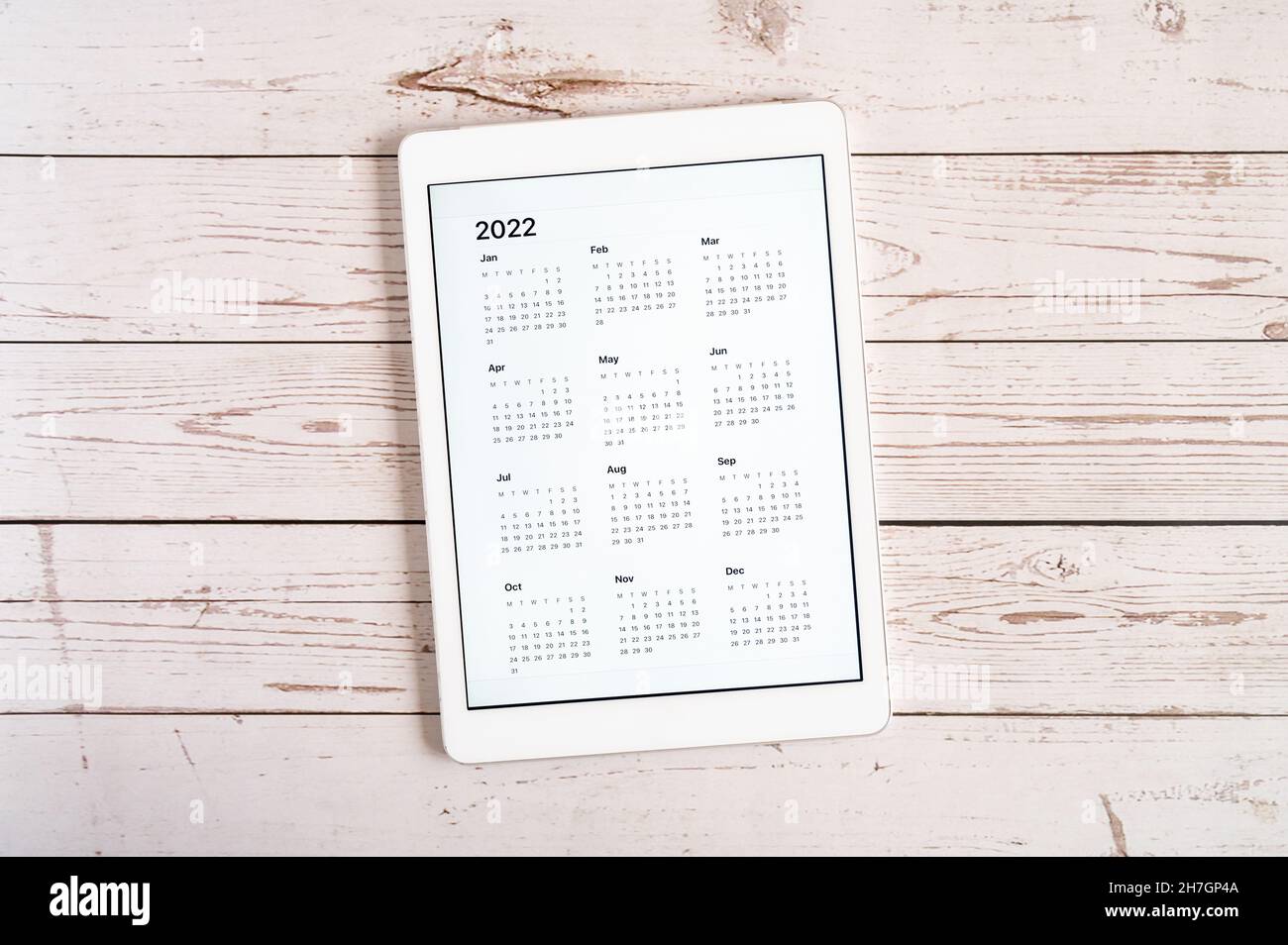 tablet computer with an open app of calendar for 2022 year on a wooden ...