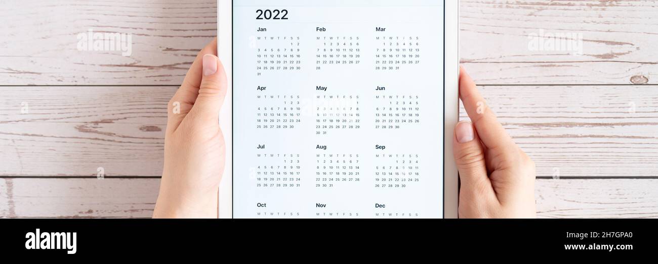 tablet computer with an open app of calendar for 2022 year in a womans ...