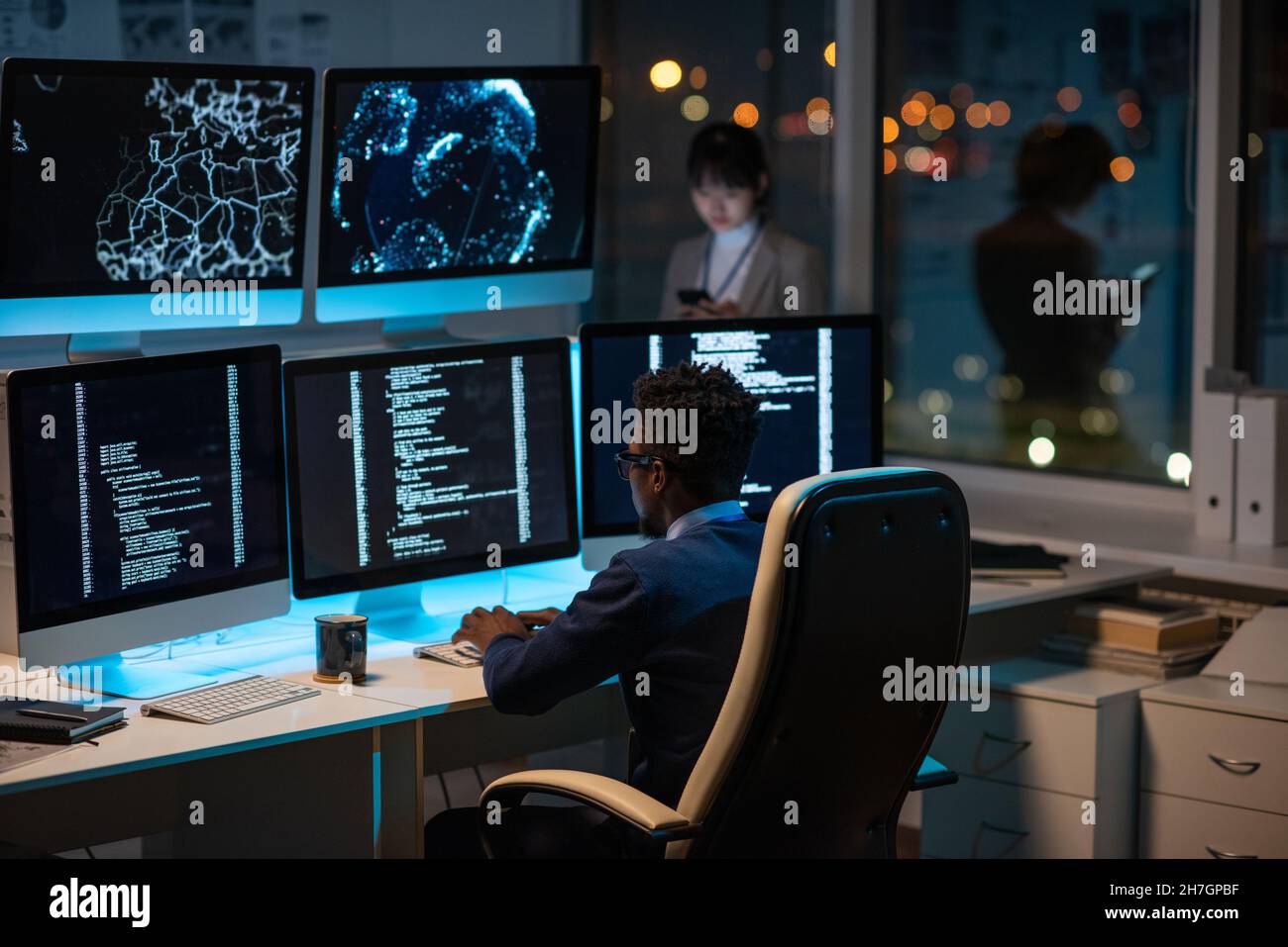 Young African it-developer typing in front of computer screen while ...