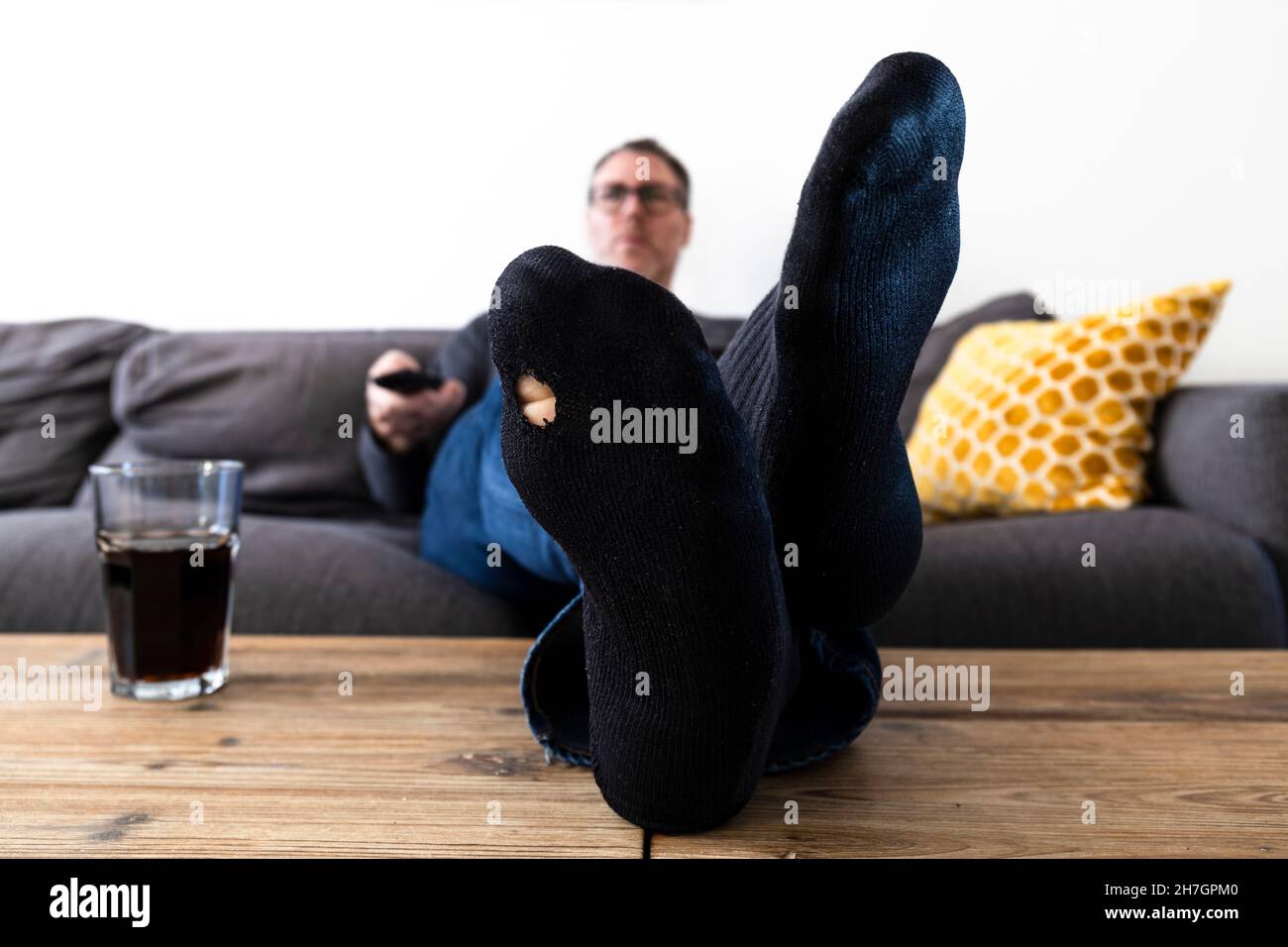 Adult man with a hole in his sock watching tv and using the remote ...