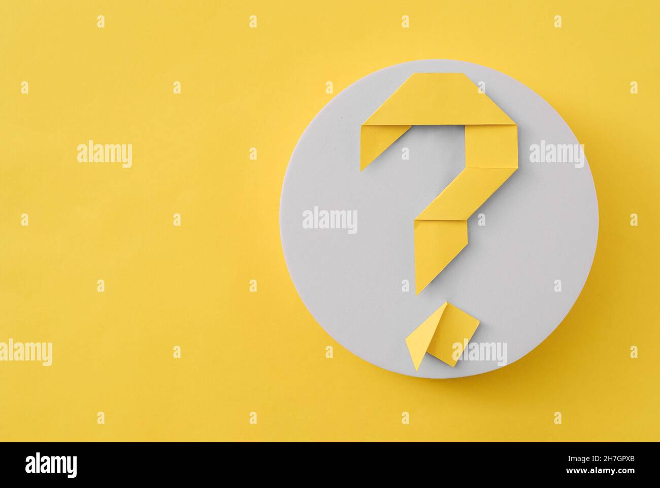Colorful yellow origami question mark on a white paper circle over a ...