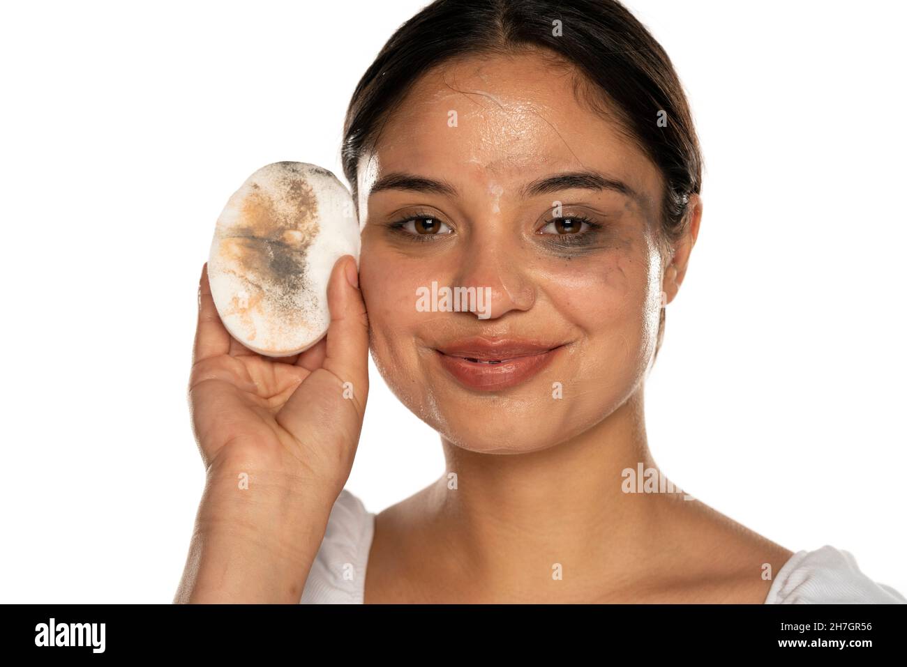 a young smiling woman shows a dirty cotton pad as she wipes her face ...