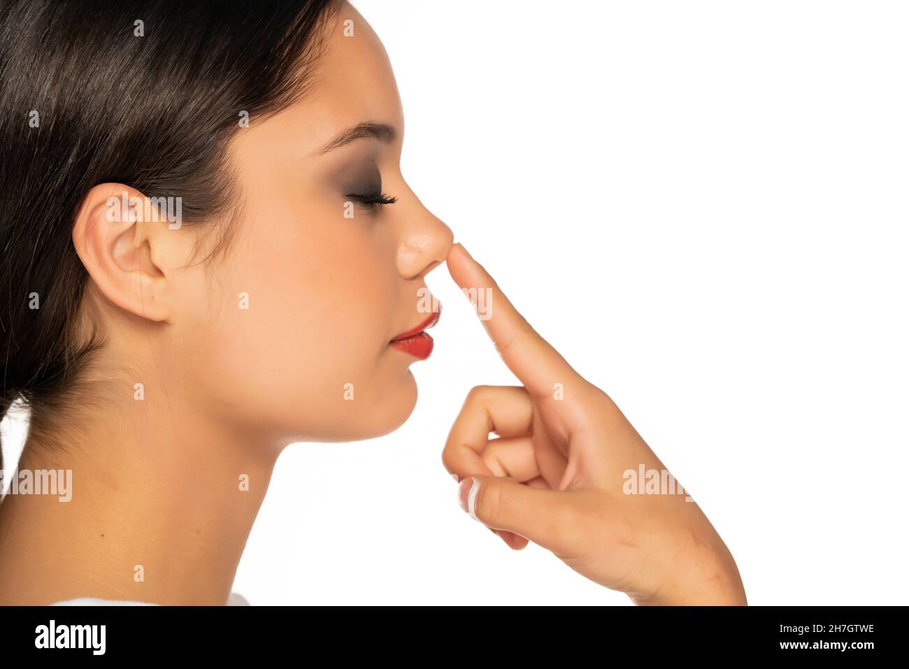 profile of a young woman touching her nose on a white background Stock ...