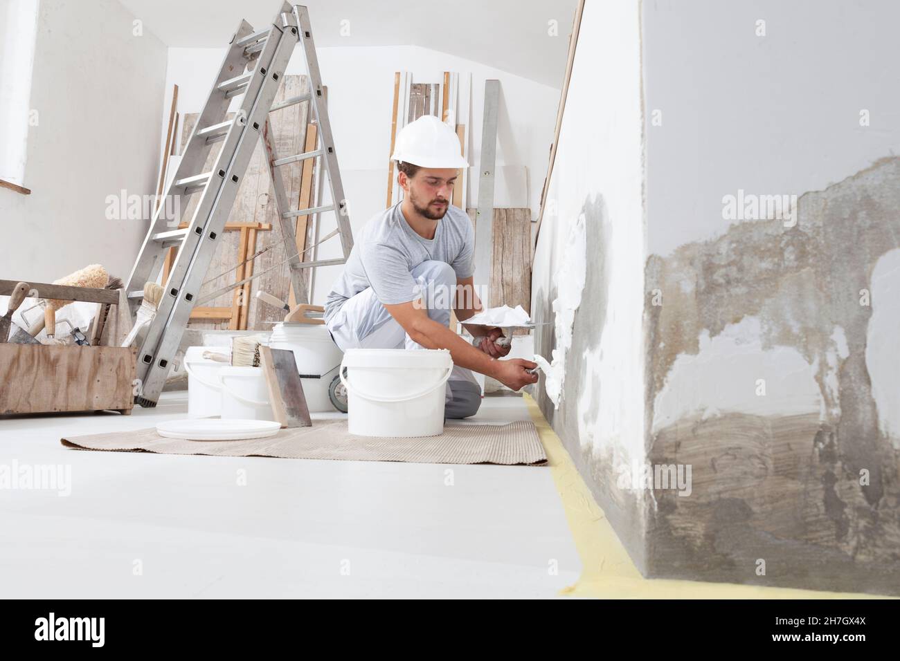 man plasterer construction worker at work, takes plaster from bucket ...