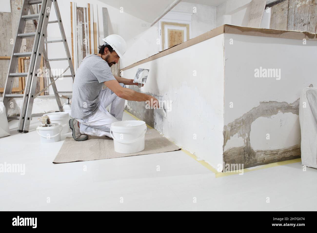 plasterer man at work, take the mortar from the bucket with trowel to ...