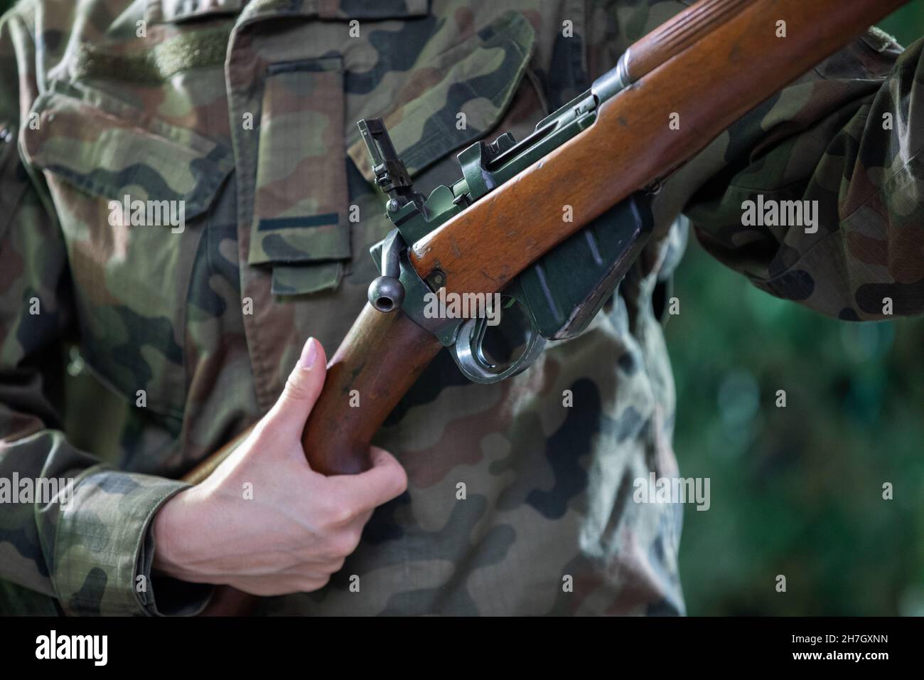 The lady soldier holds a loaded rifle up to the ceiling right in front ...