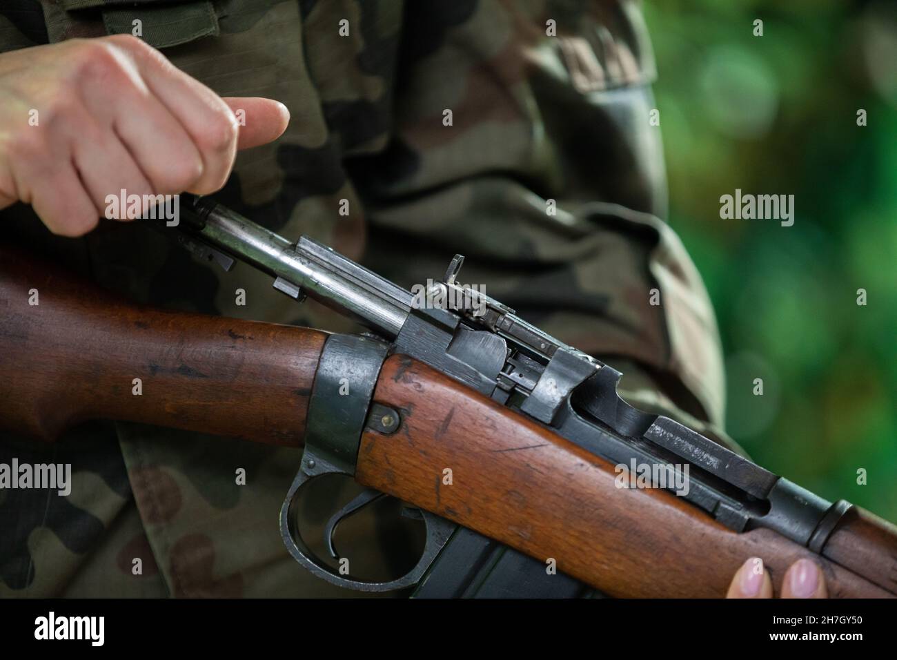A lady soldier pulls back the lock of a self-reloading rifle to reload ...