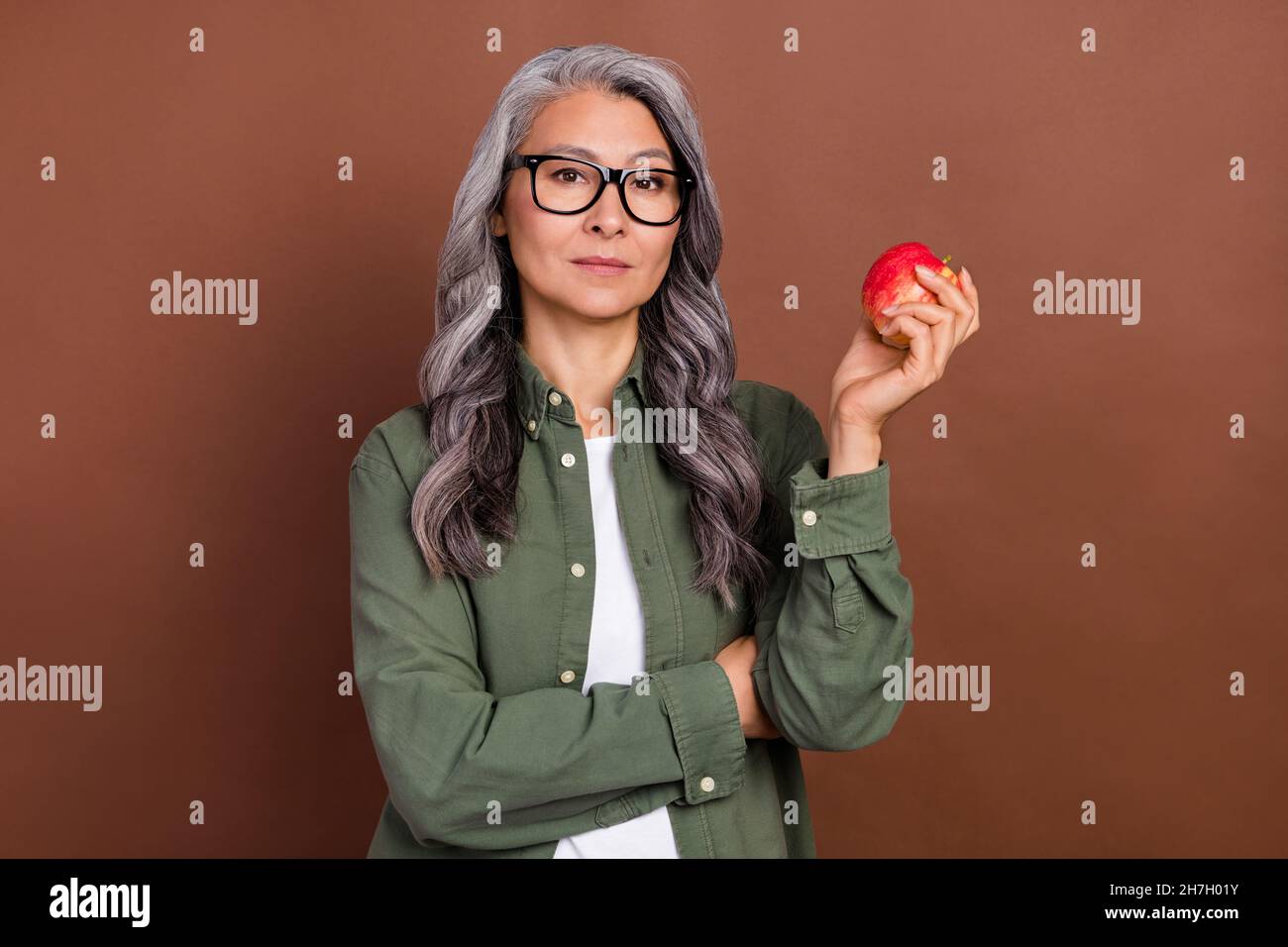 Photo of good elder grey hairdo lady hold apple wear shirt eyesight ...