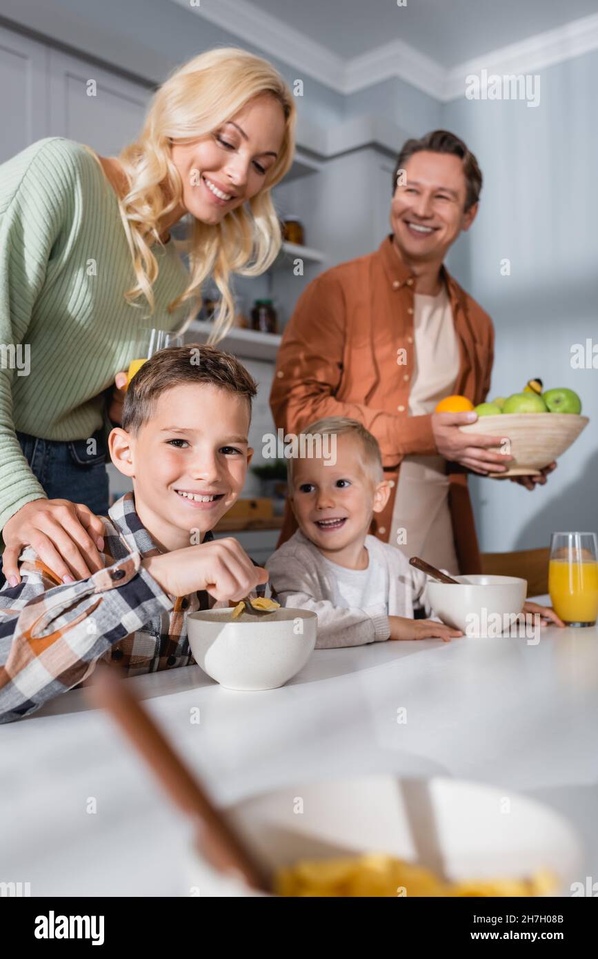 happy brothers eating corn flakes near happy parents in kitchen Stock ...