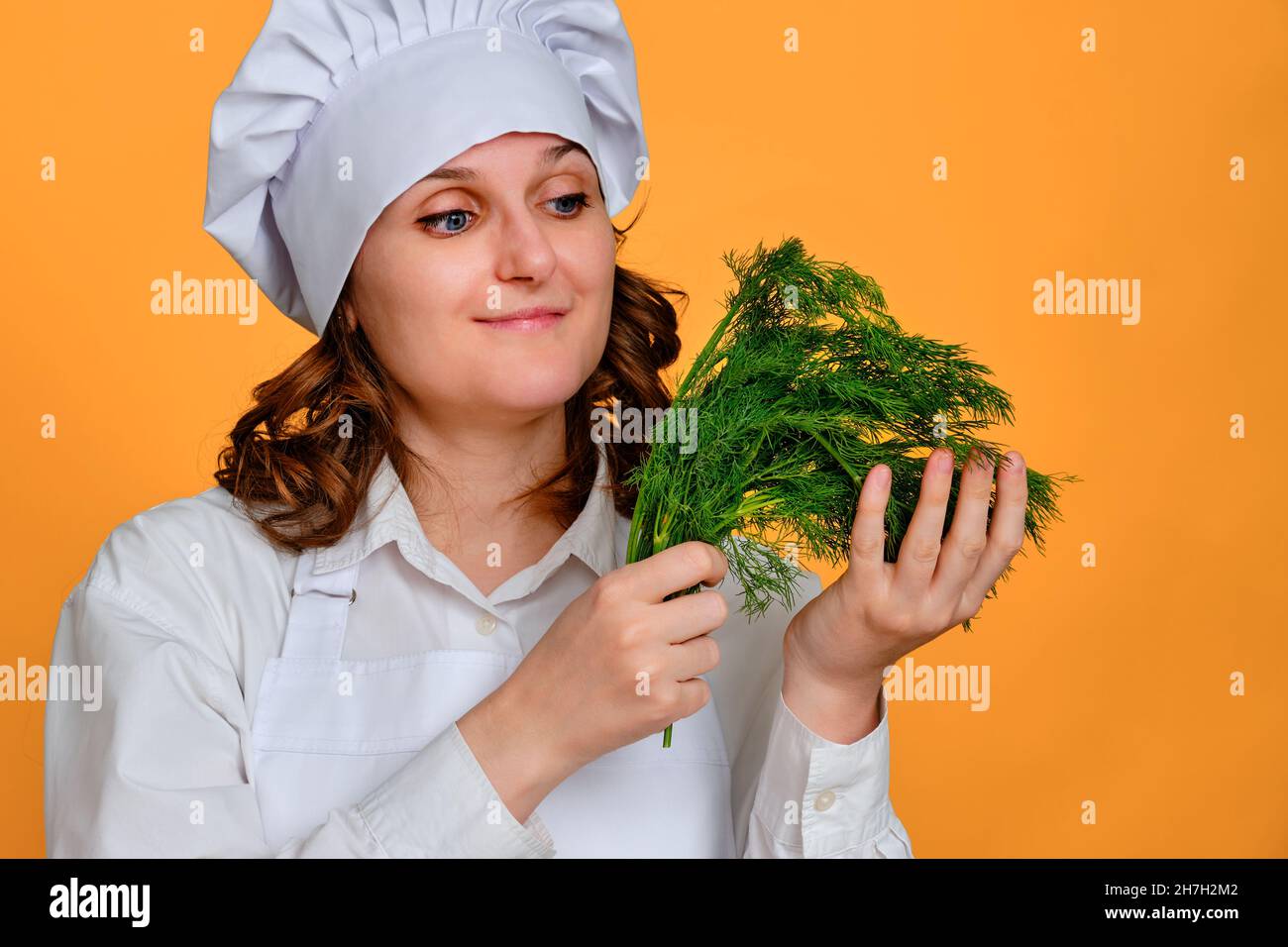 Female chef with herb of spices in her hands on a studio background ...