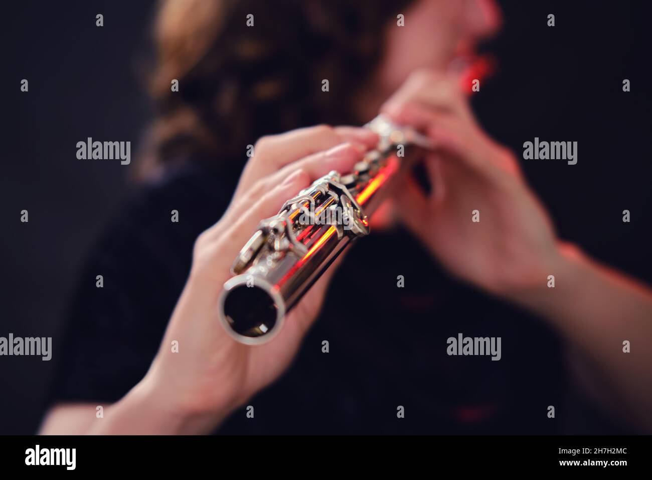 Portrait of a woman musician with a flute on a studio black background ...